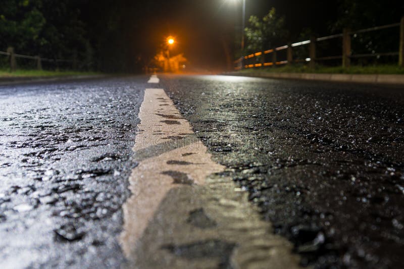 A Low Angle Shot of an Empty Road on a Misty Night with Street Lights ...