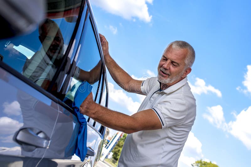 Low Angle Shot of an Old Male Wiping the Windows of His Car Under a ...