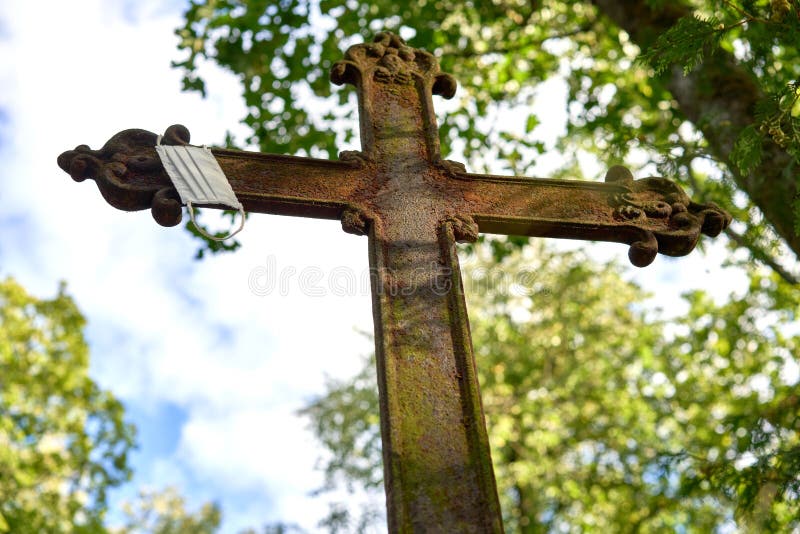 Low-angle Shot of a Rusty Metal Cross with a Facemask Hanging on it in ...