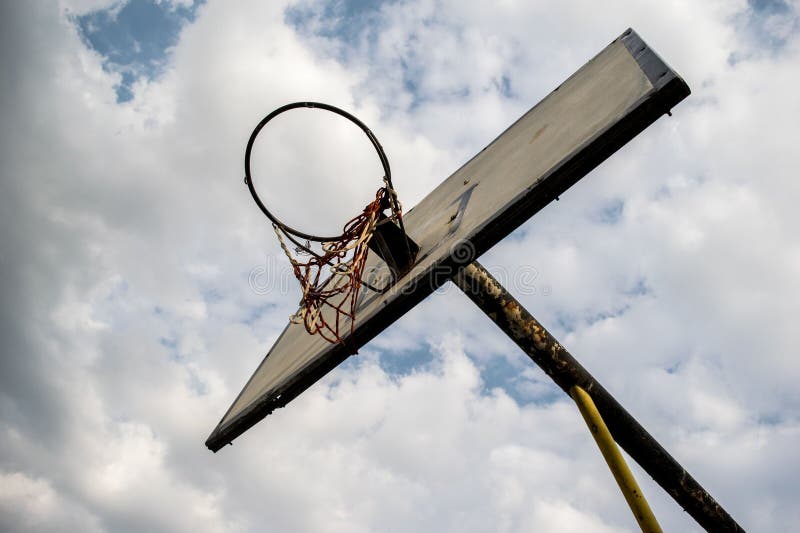 Low Angle Shot of a Rusty Old Basketball Hoop Under a Cloudy Blue Sky ...