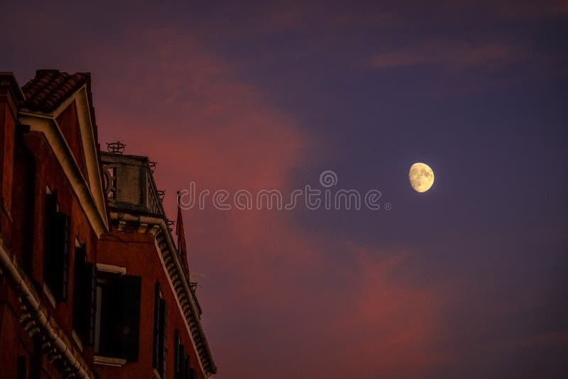 Low Angle Shot of a Tall Building with a Visible Moon in the Purple and ...