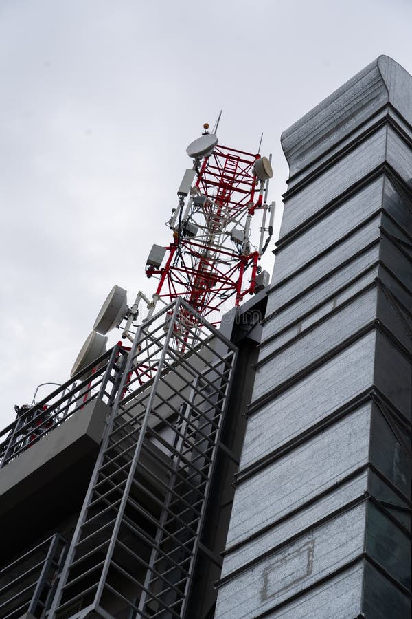 Low Angle Shot of a Telecom Tower on a Modern Building and a Gray Sky ...