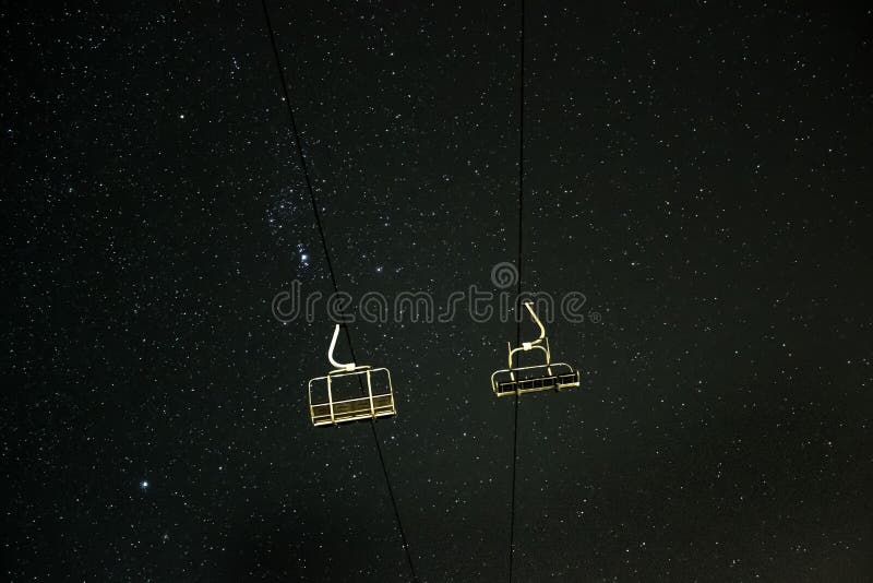 Low Angle Shot of Two Cable Car Seats Hanging Under a Starry Night Sky ...
