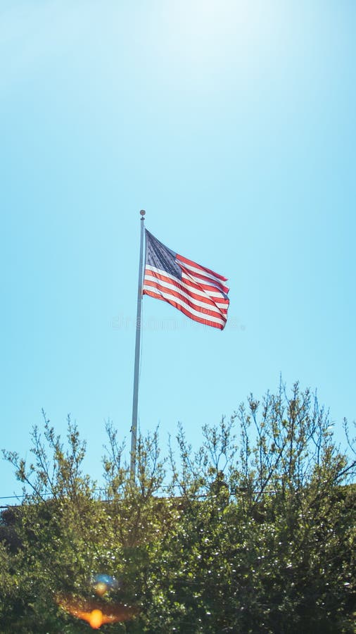 Low-angle Shot of the US Flowing Flag in the Blue Sky with Sun Shining ...