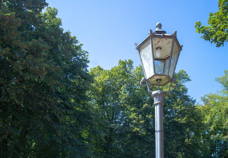 Low Angle Shot of a Vintage Lamp Post with Broken Glass and Trees on ...