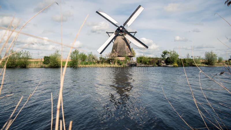 Low-angle Shot of a Windmill in Front of a River with a Cloudy Sky in ...