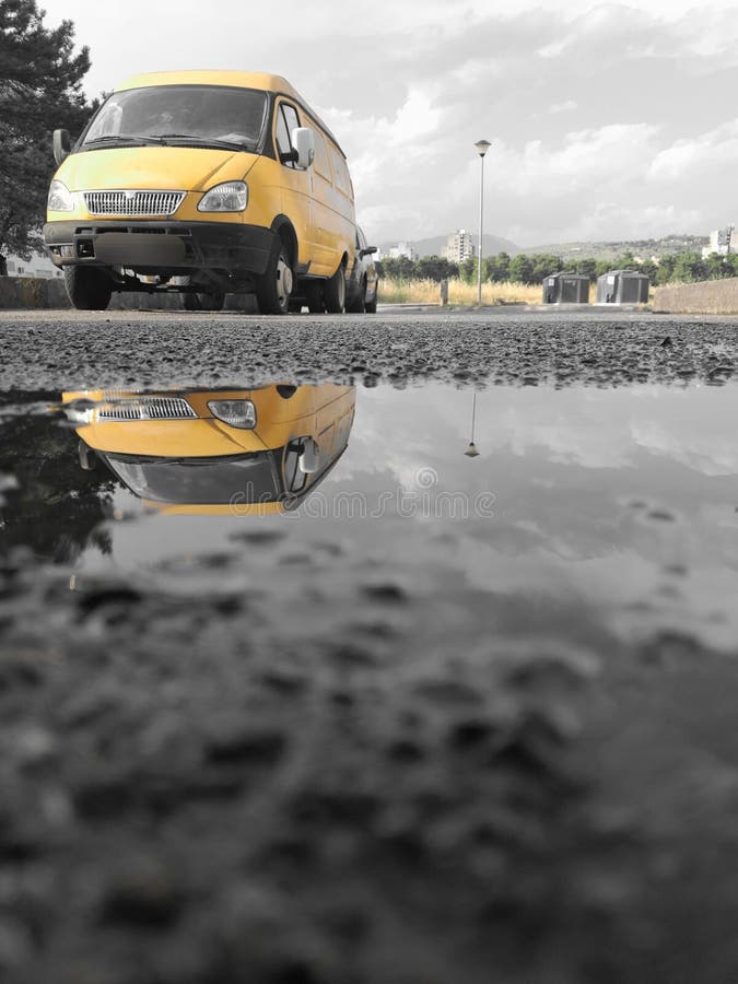 Low-angle Shot of a Yellow Van Reflection Captured in a Water Puddle on ...