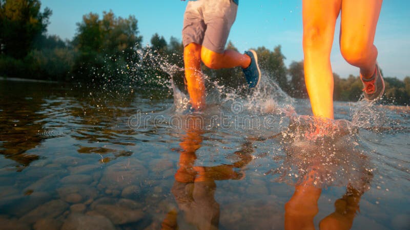 LOW ANGLE: Unrecognizable Couple Jogging in the Shallows of a Tranquil ...
