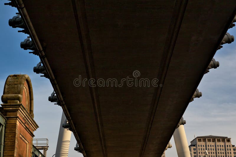 Underside of Concrete Bridge Structure with Brick Building and Sky in ...