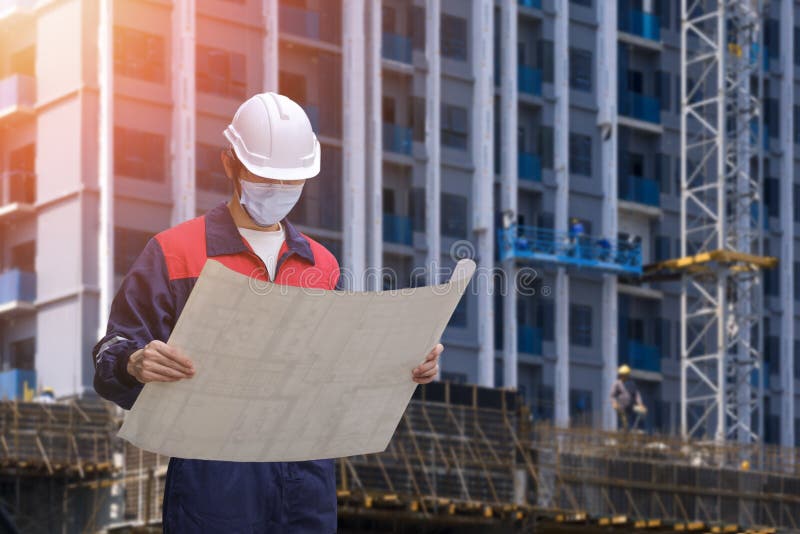 Engineer Builder in Protective Face Mask Looking at Project Blueprint ...