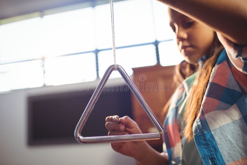 Portrait of Girl Playing Triangle in Classroom Stock Photo - Image of ...