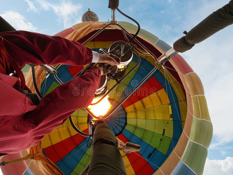 Low Angle View of Man Operating Hot Air Balloon, Giving it a Boost in ...