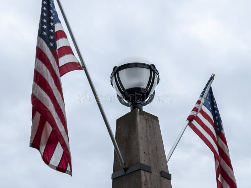 View of Two American Flags Attached To a Lamp Post Against a Cloudy ...