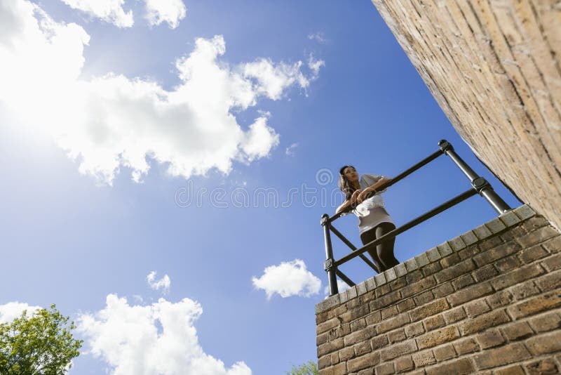 Low Angle View of Young Woman Leaning on Railing Stock Photo - Image of ...