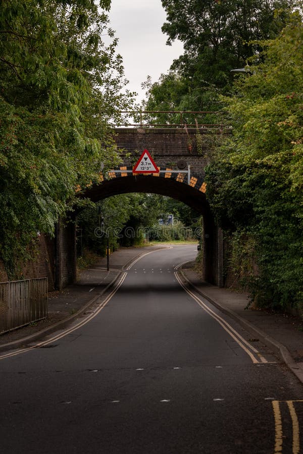 Low Bridge Warning Sign Over Empty Road Passing Under a Railway Bridge ...