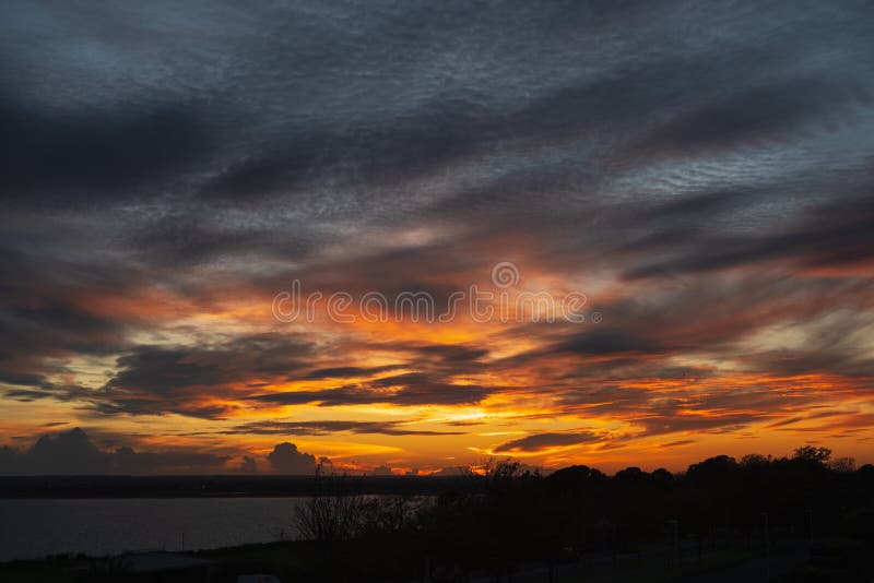 Low Clouds Forming a Dramatic, Fiery Sky at Sunset Over Water Stock ...