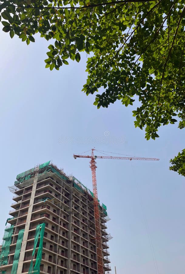 Low Focus on a Building Under Construction with a Crane, and a Green ...