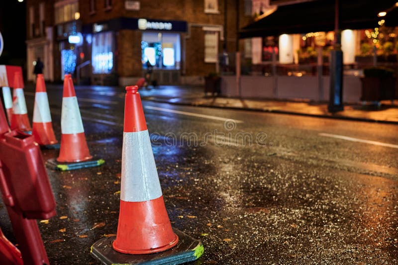 Low View of Roadwork Cones on Wet Street at Night with Blurred ...