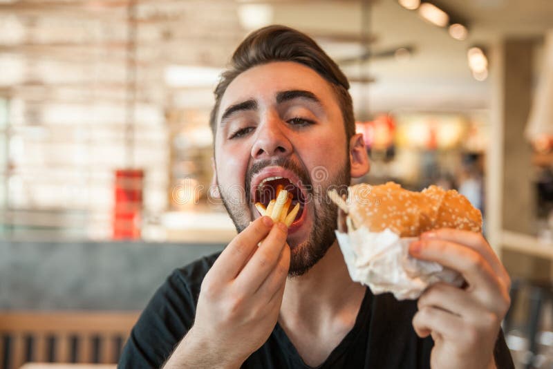 Lunch at the Cafe. a Man Eats French Fries and Keeps a Burger Stock ...