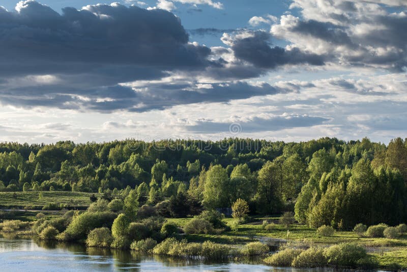 Lush Green Trees Line a River Under a Dramatic Cloudy Sky Stock Photo ...