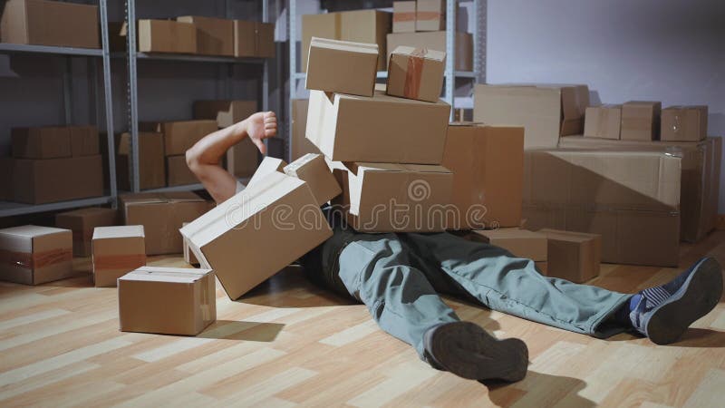 A Lying Male Loader Falling with Boxes Shows His Finger Down Stock ...