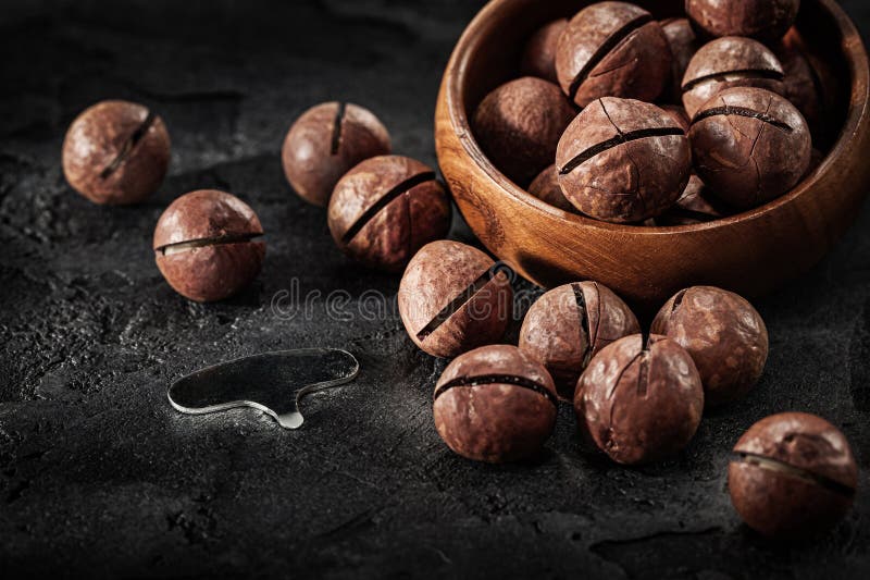 Macadamia Nuts and Key for Open it with Wooden Bowl on Black Background ...