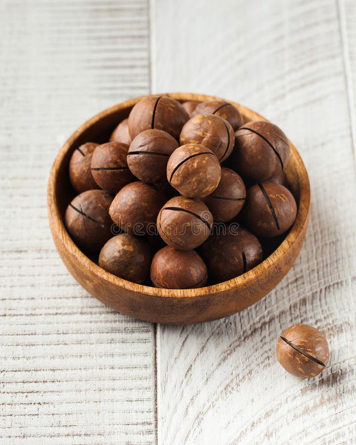 Macadamia Nuts in a Shell in a Wooden Plate on a White Wooden ...