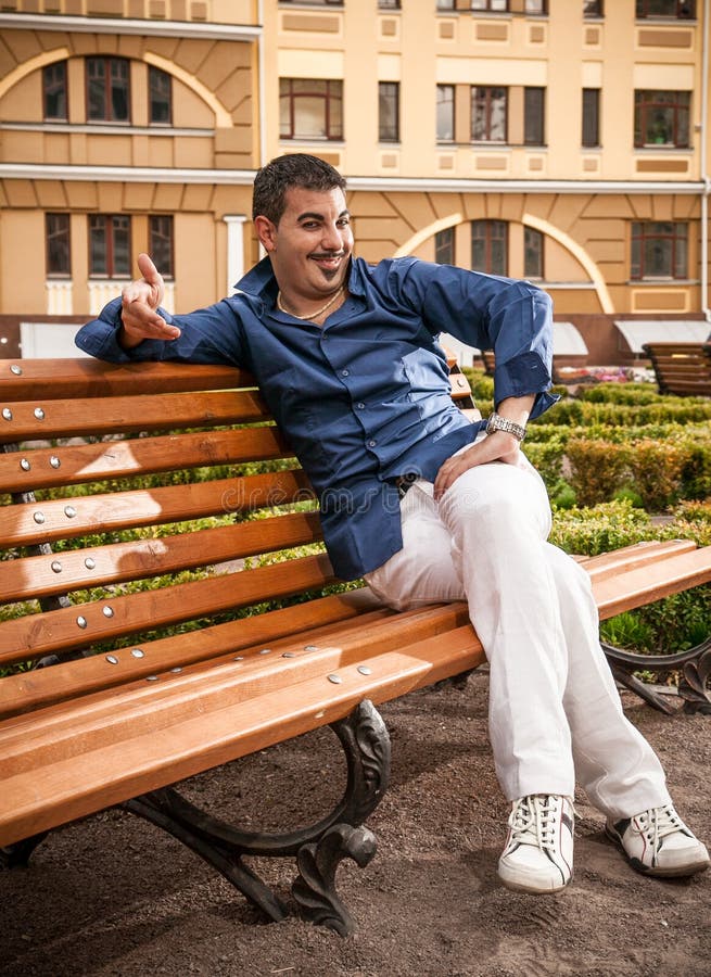 Macho man sitting on bench stock image. Image of city - 34256695