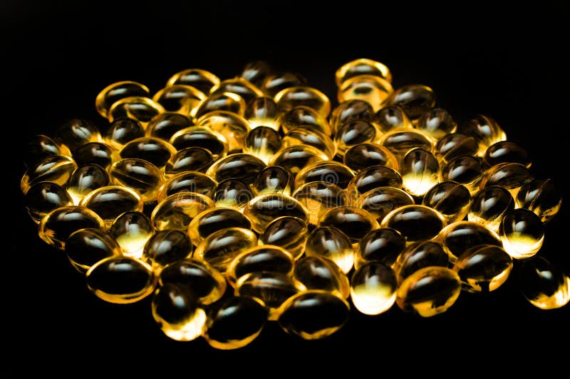 Macro Close Up of Omega 3 Gel Capsule on a Reflective Black Background ...