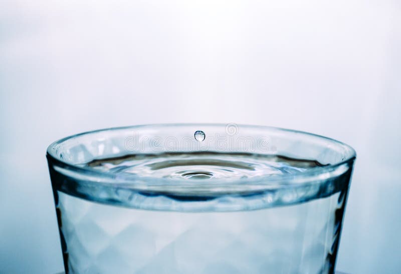 Macro Shot of a Drop of Water Falling into a Glass Cup with Drinking ...
