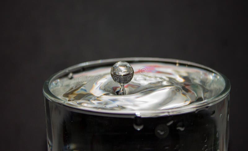 Macro Shot of a Drop of Water Over an Overflowing Glass on a Dark ...