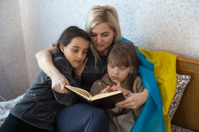 Madre E Hija Leyendo Un Libro Con La Bandera De Ucrania En La Cama ... Madre E Hija Leyendo Un Libro Con La Bandera De Ucrania En La Cama ...