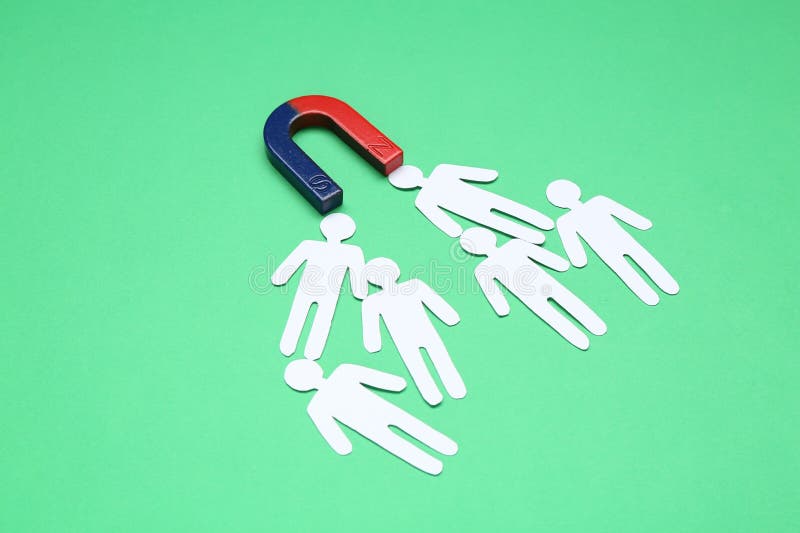 Magnet Attracting Paper Human Figures on Green Background Stock Image ...