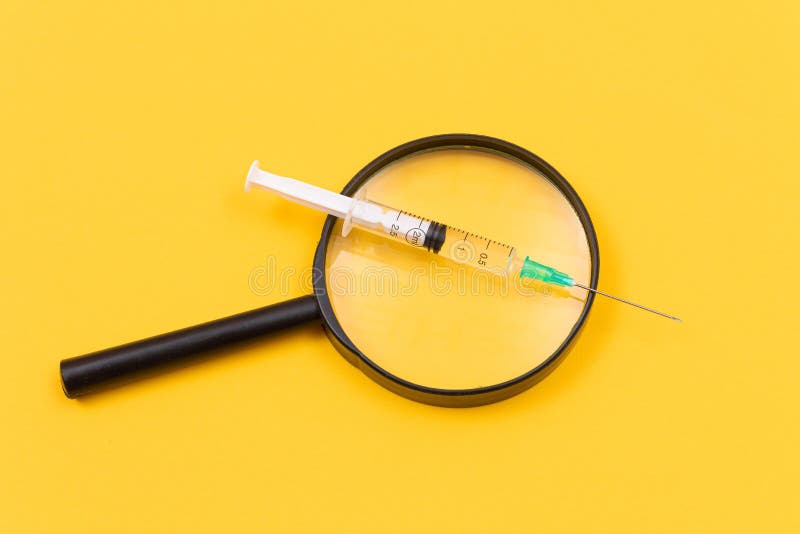A Magnifier with Medical Syringe on Yellow Table Stock Image - Image of ...
