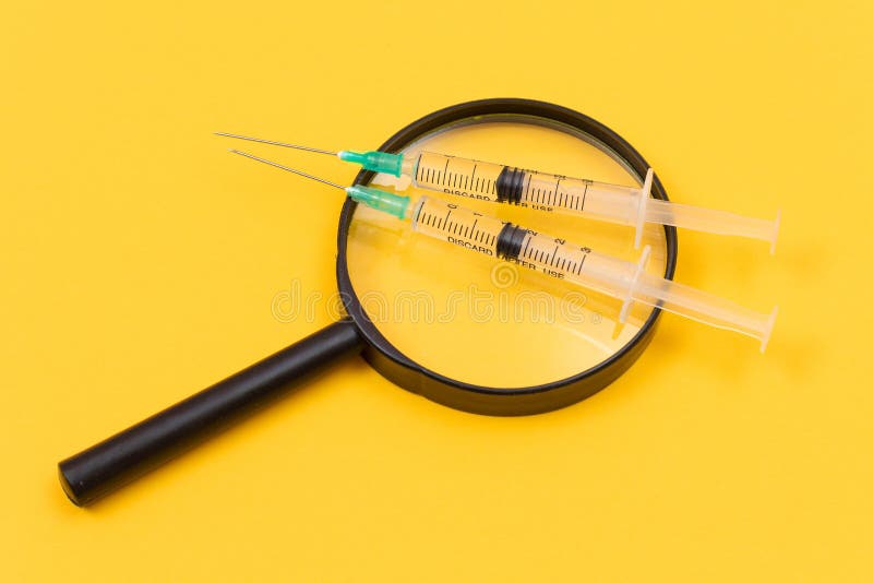 A Magnifier with Medical Syringe on Yellow Table Stock Image - Image of ...
