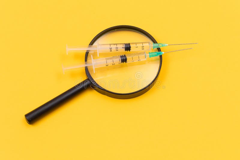 A Magnifier with Medical Syringe on Yellow Table Stock Photo - Image of ...
