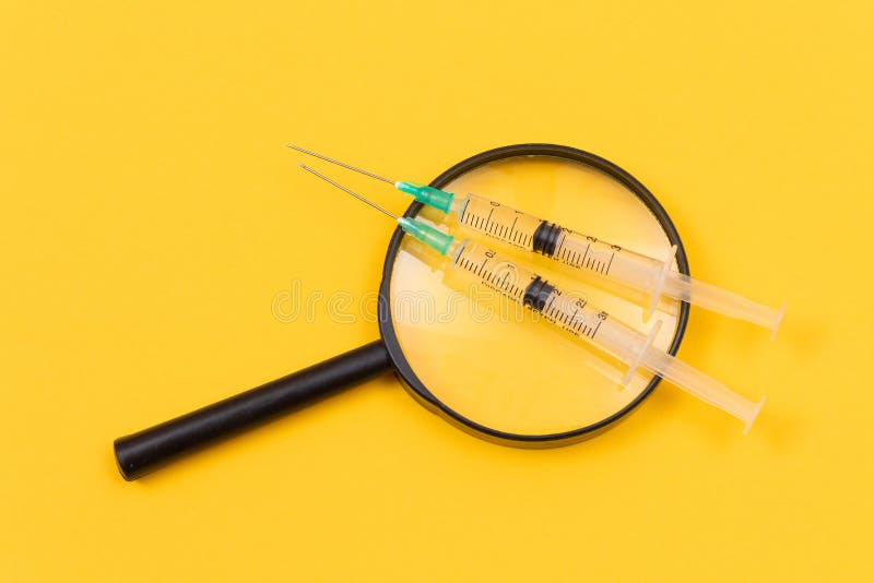 A Magnifier with Medical Syringe on Yellow Table Stock Image - Image of ...