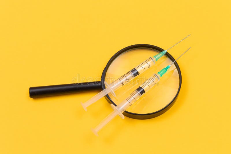 A Magnifier with Medical Syringe on Yellow Table Stock Image - Image of ...