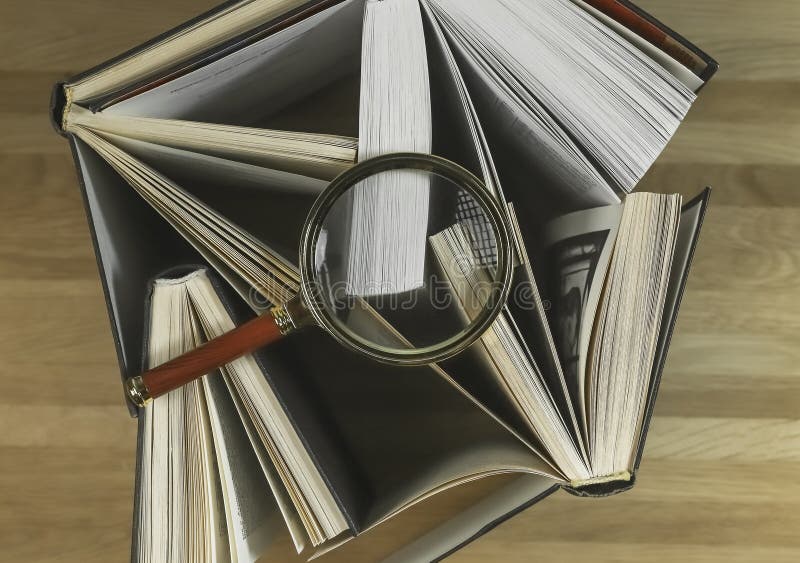 Magnifying Glass Over Books on Wood Table, Top View. Reading and ...