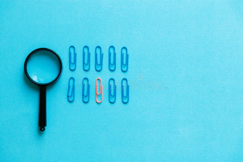 A Magnifying Glass and Paper Clips on a Blue Background Stock Photo ...