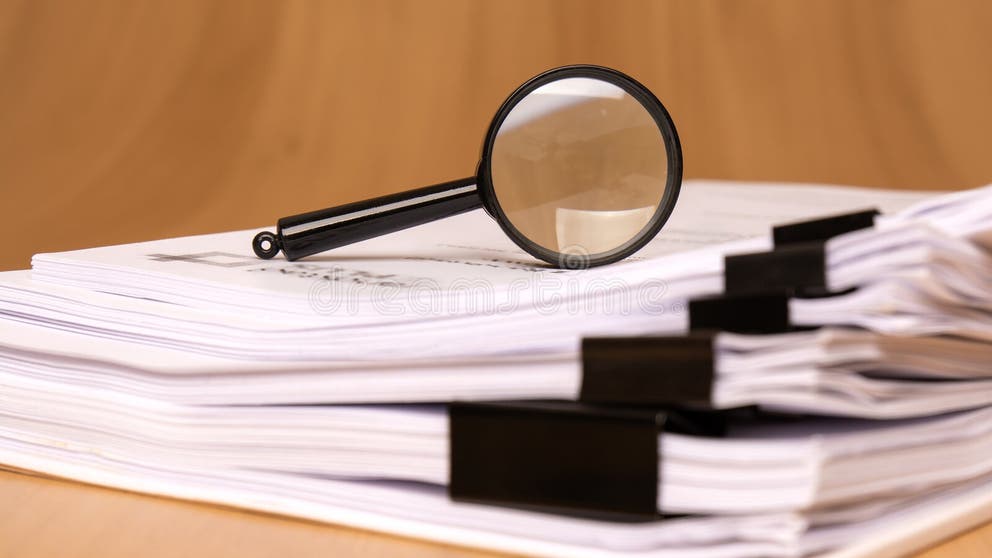 A Magnifying Glass that is Positioned on a Stack of Papers, Which are ...