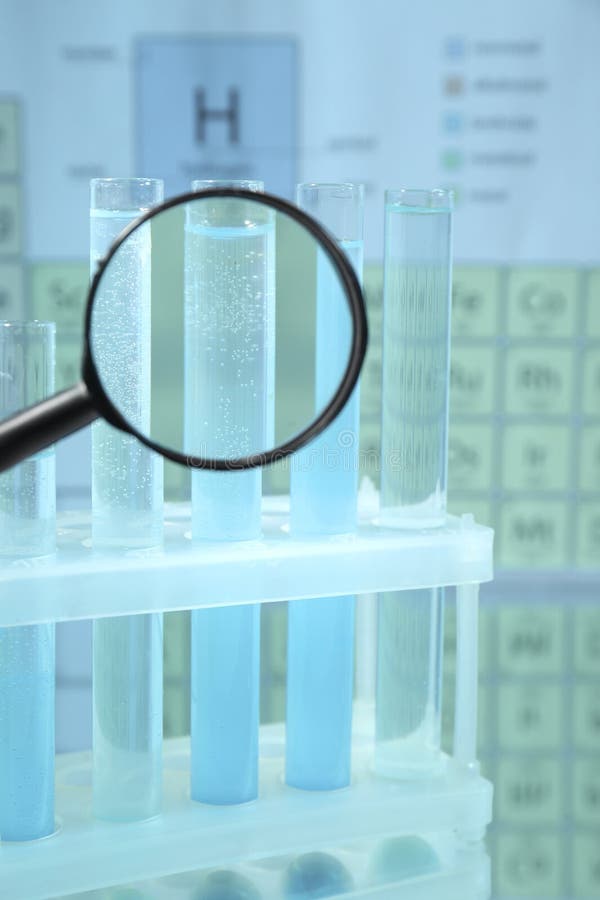 Magnifying Glass and Test Tubes in Rack on Mirror Surface Against ...