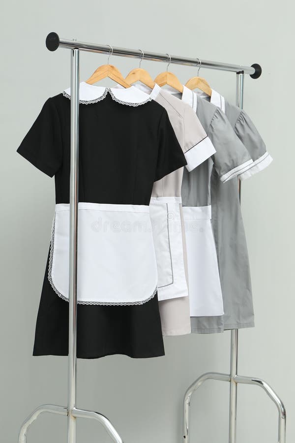Maids Uniforms on Clothing Rack Against Grey Background Stock Photo ...