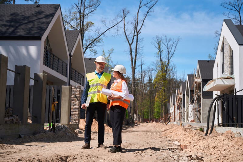 Main Construction Workers Walking Along Construction Site, Discussing ...