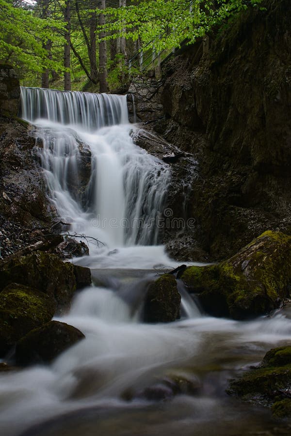 A Waterfall is Flowing Over Some Large Rocks in a Forest Stock Photo ...