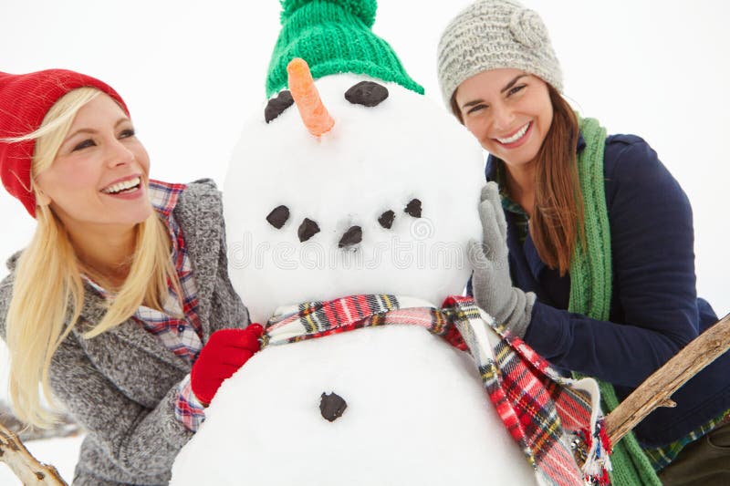 Make-over Time for the Snowman. Two Gorgeous Young Women Building a ...