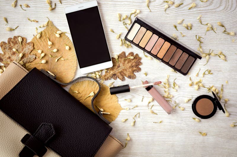 Make-up Stuff, Mobile Phone and Female Bag on White Table with Leaves ...