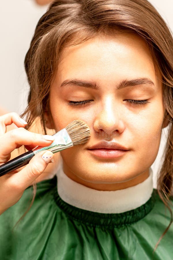 The Makeup Artist Applies a Cosmetic Tonal Foundation on the Face Using ...