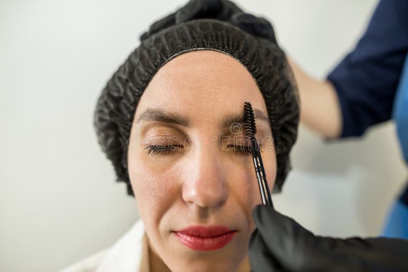 Makeup Artist Combing the Eyebrows of a Beautiful Young Woman before ...