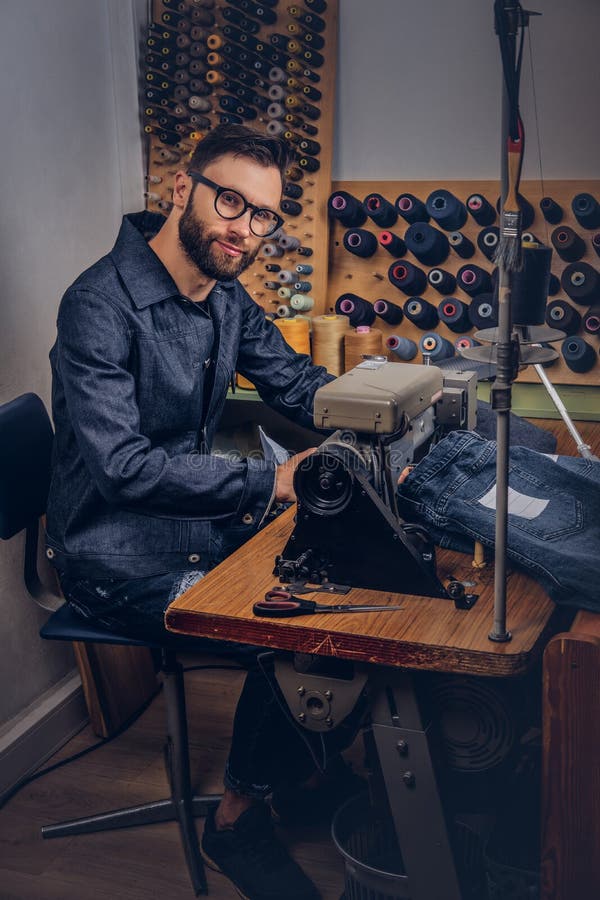 Tailor Sitting at Table with Sewing Machine and Looking at a Camera in ...